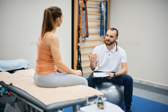 Professional physiotherapist talking to female patient at physical therapy center. Stock Photo ...